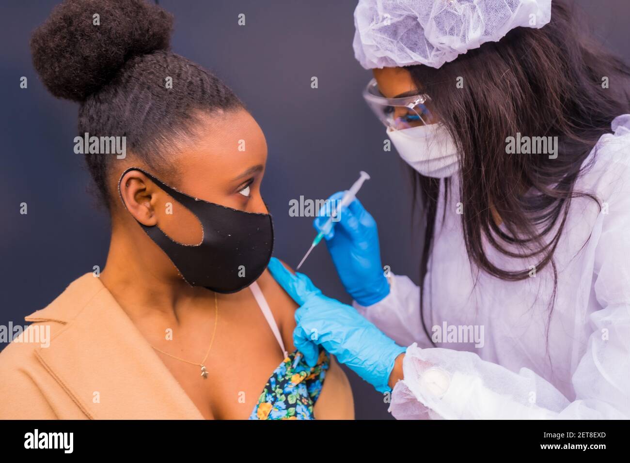 An African-American young female receiving the injection of the COVID ...