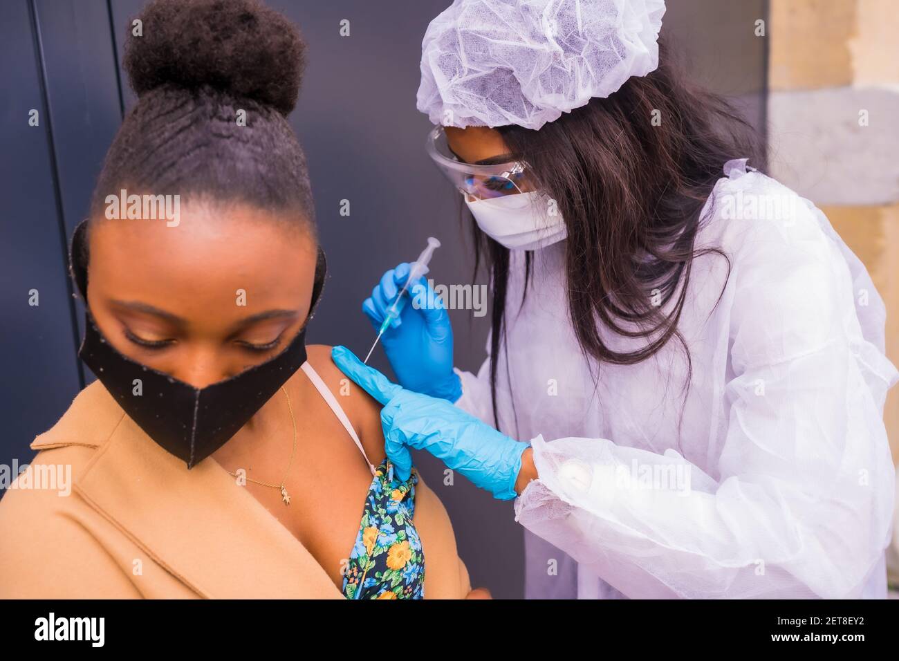 An African-American young female receiving the injection of the COVID ...