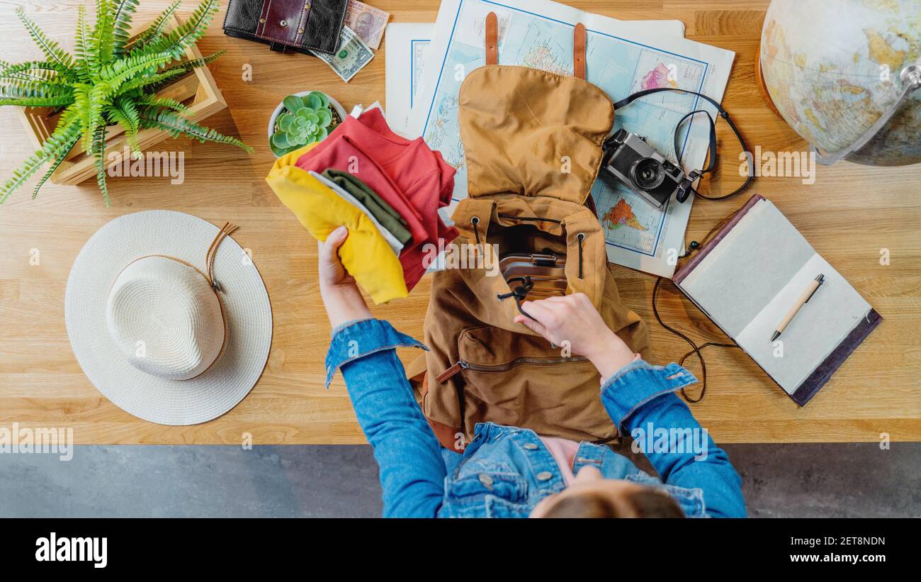 Top view of young woman packing for vacation trip holiday, desktop ...