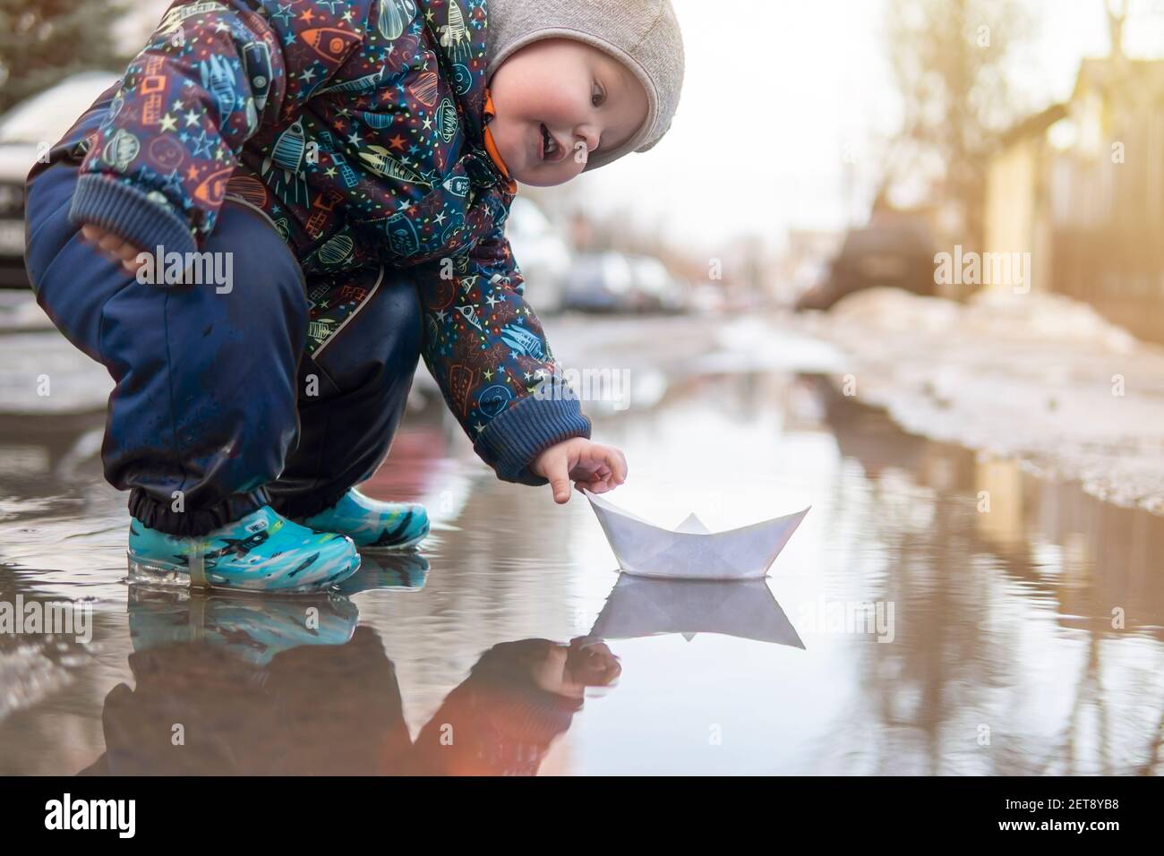 Little boy plays with paper ships in a spring puddle Stock Photo - Alamy