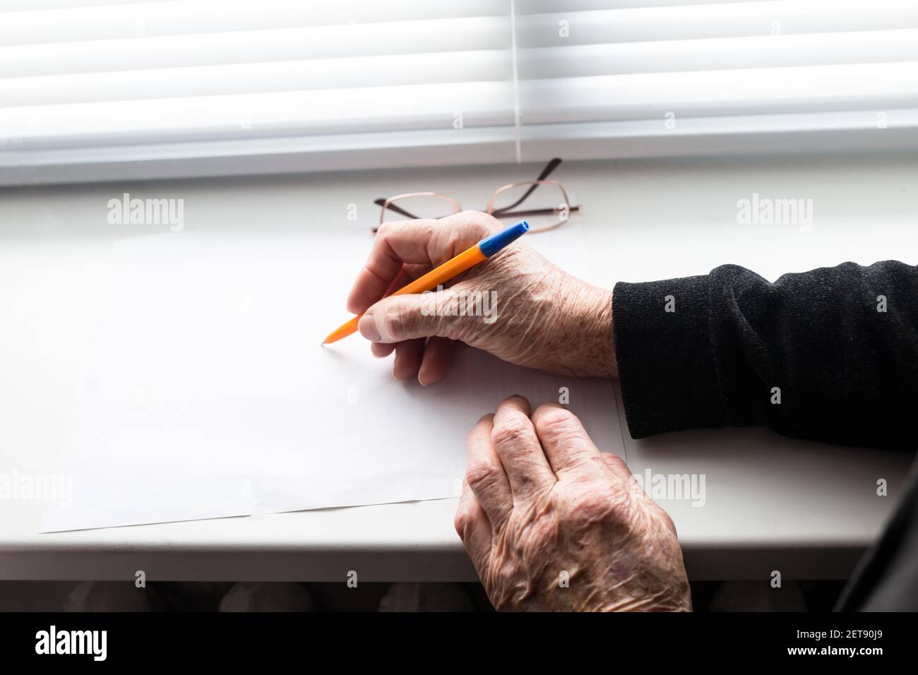 Hands of old woman with pen writing on piece of paper, next to the ...