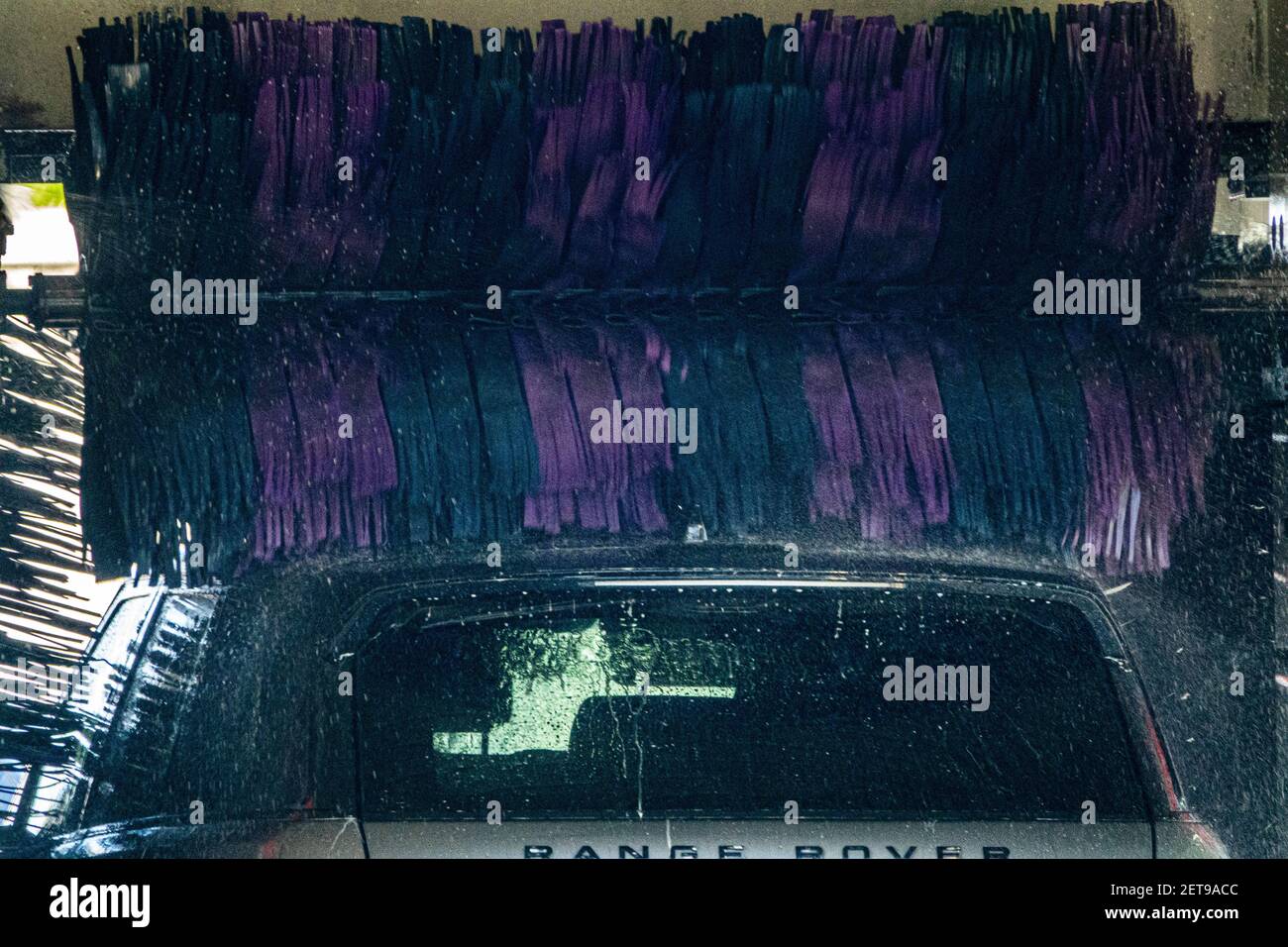 A car (silver Range Rover) being washed in an automated machine jet car ...