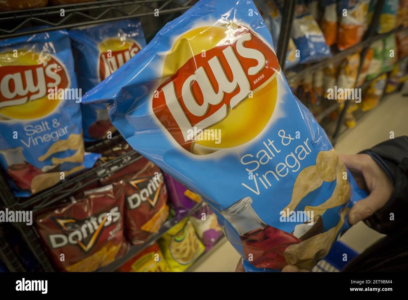 A shopper chooses a bag of PepsiCo Frito-Lay brand potato chip snacks ...