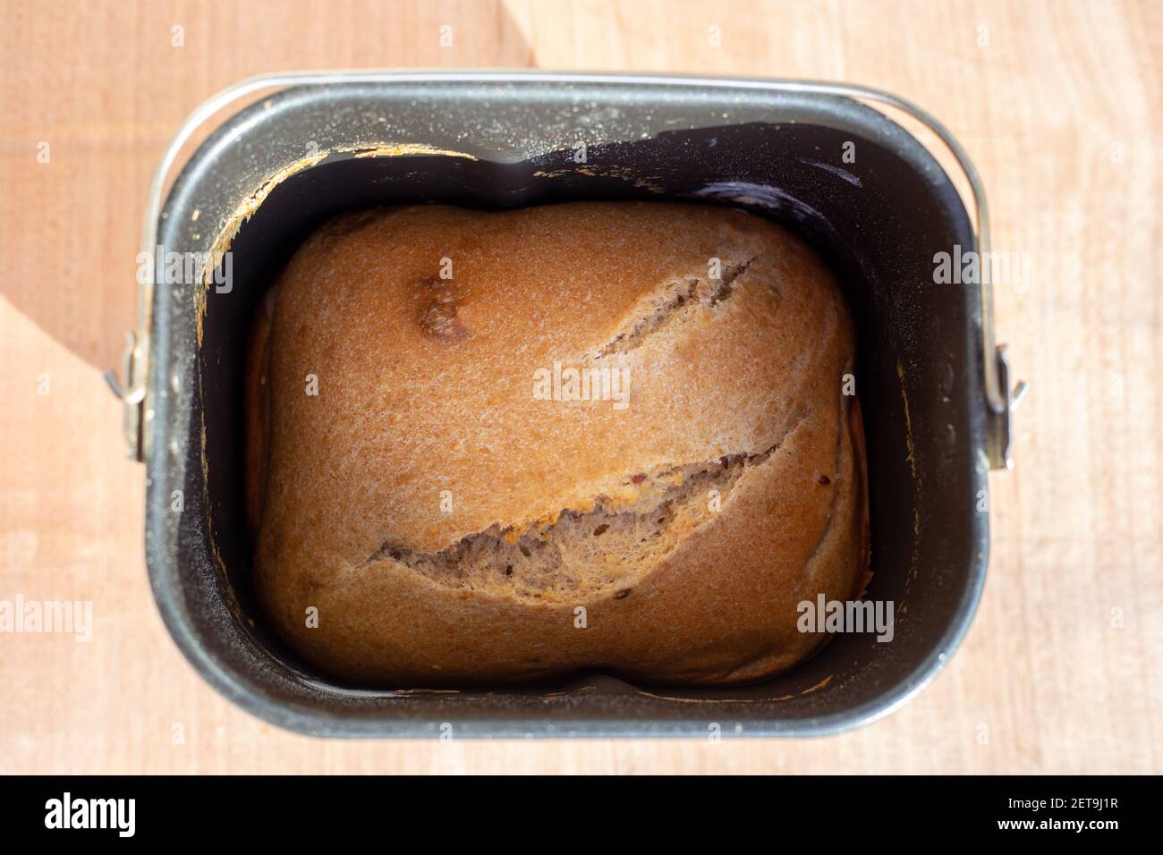 A loaf of baked fresh bread in an electric bread maker. The upper crust ...