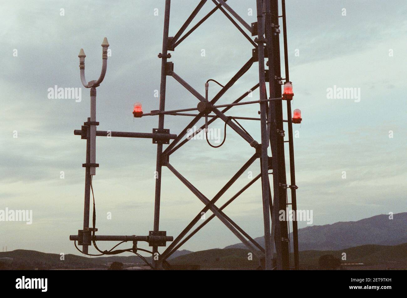 Close-up of metal structure of a cellphone tower, with antennas and red ...
