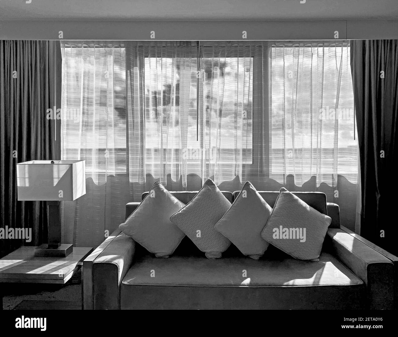 A grayscale shot of a comfortable living room overlooking the ocean ...