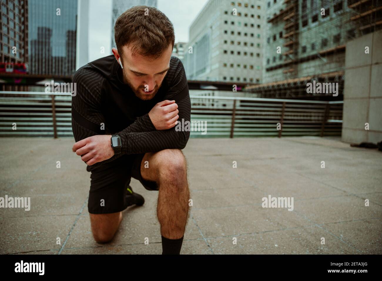 Caucasian male athlete taking a break kneeling down after long workout ...