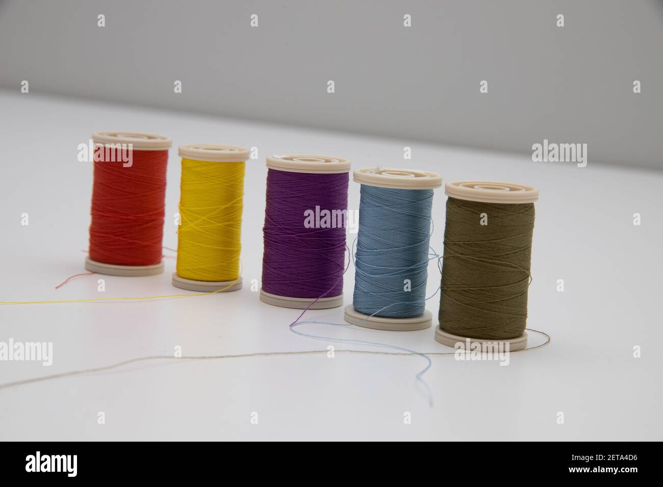A closeup of multi-colored thread spools in the light background ...