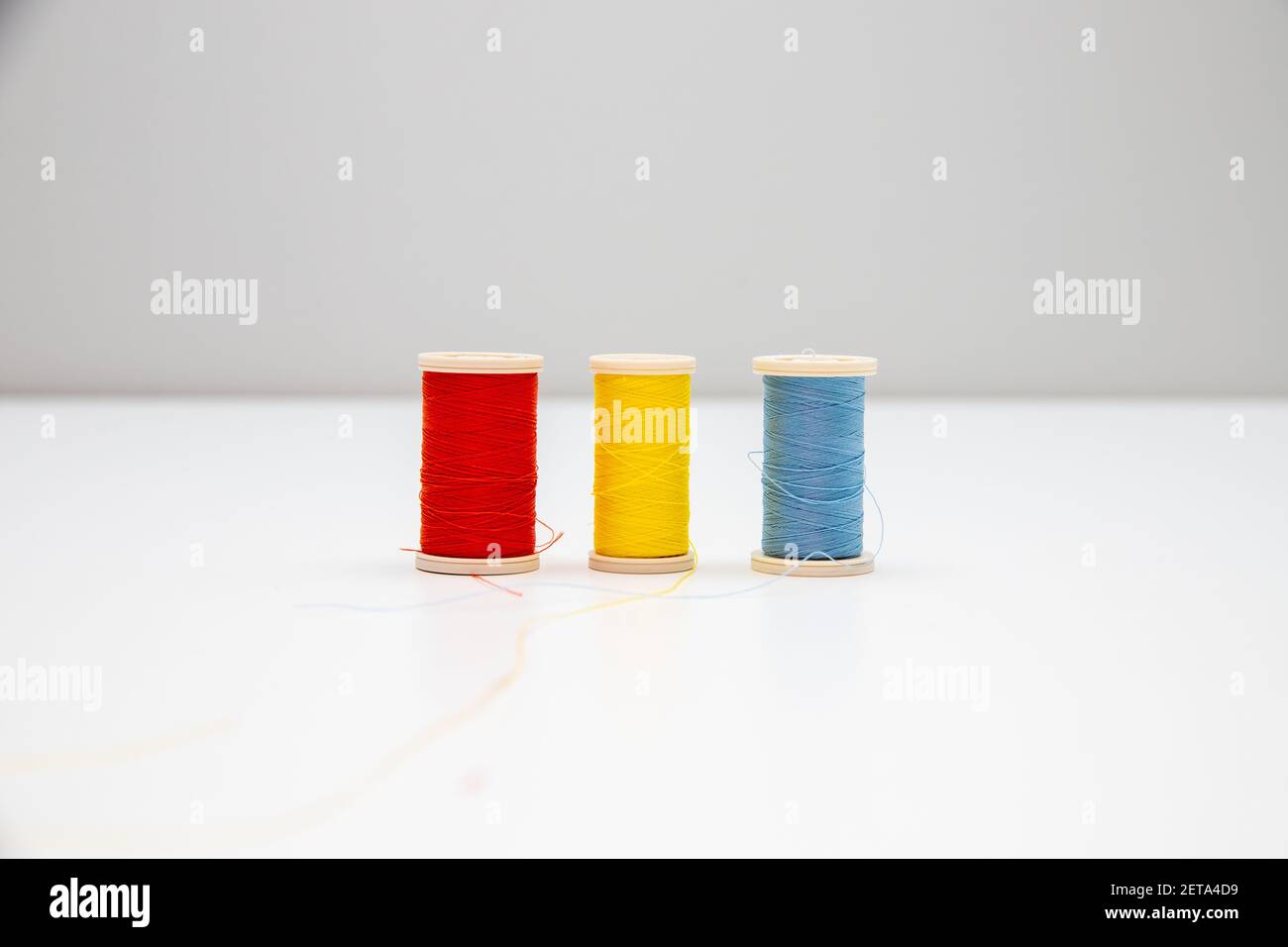 Three colorful thread spools in the light background Stock Photo - Alamy