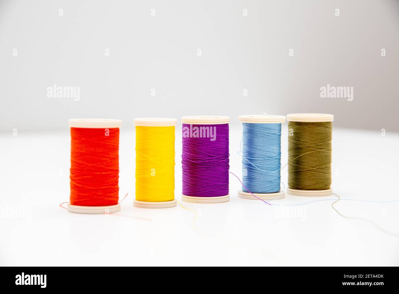 Five multi-colored thread spools isolated in the light background ...