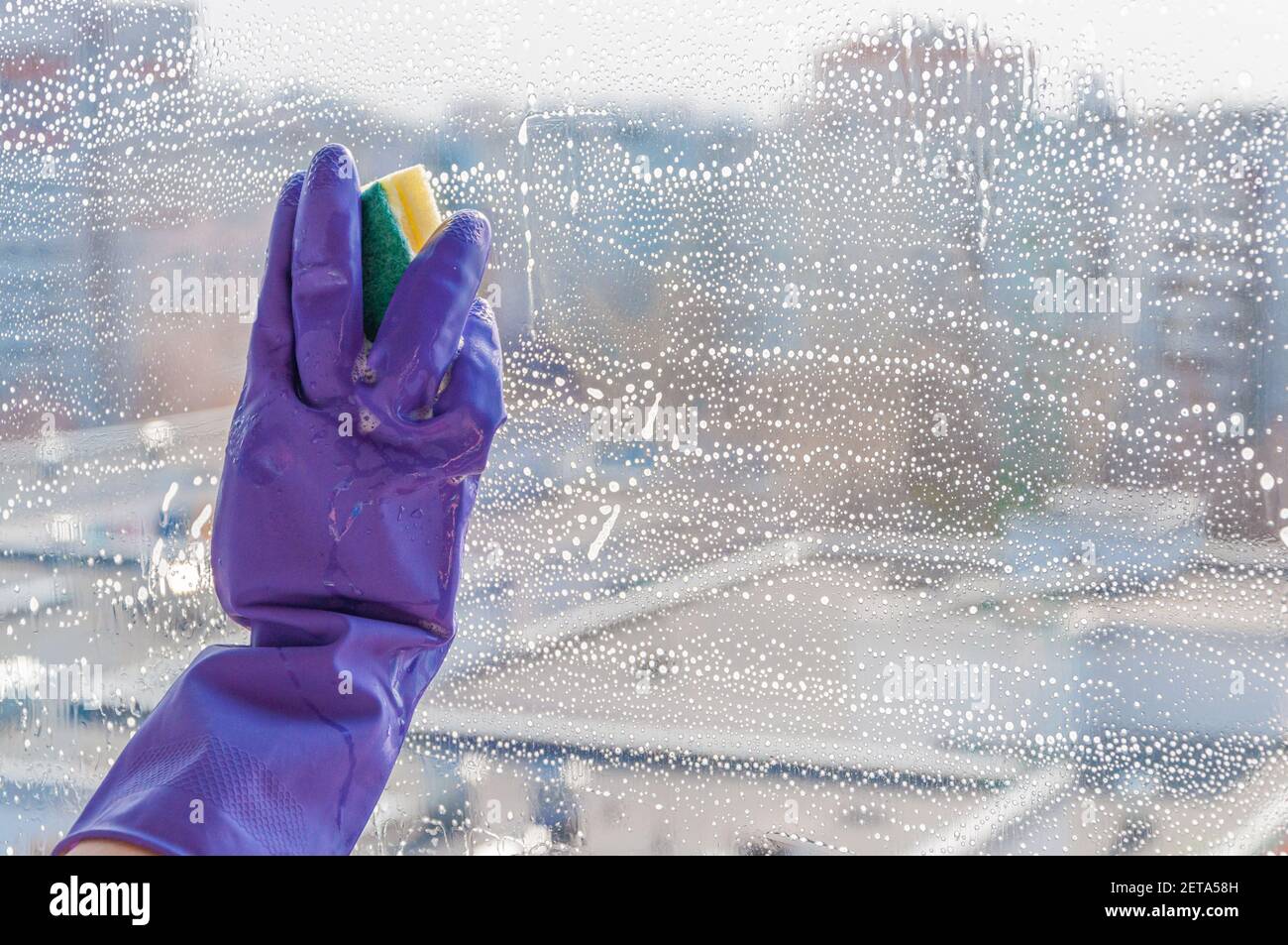 Women's hands in blue gloves washing a dusty window with a sponge Stock ...