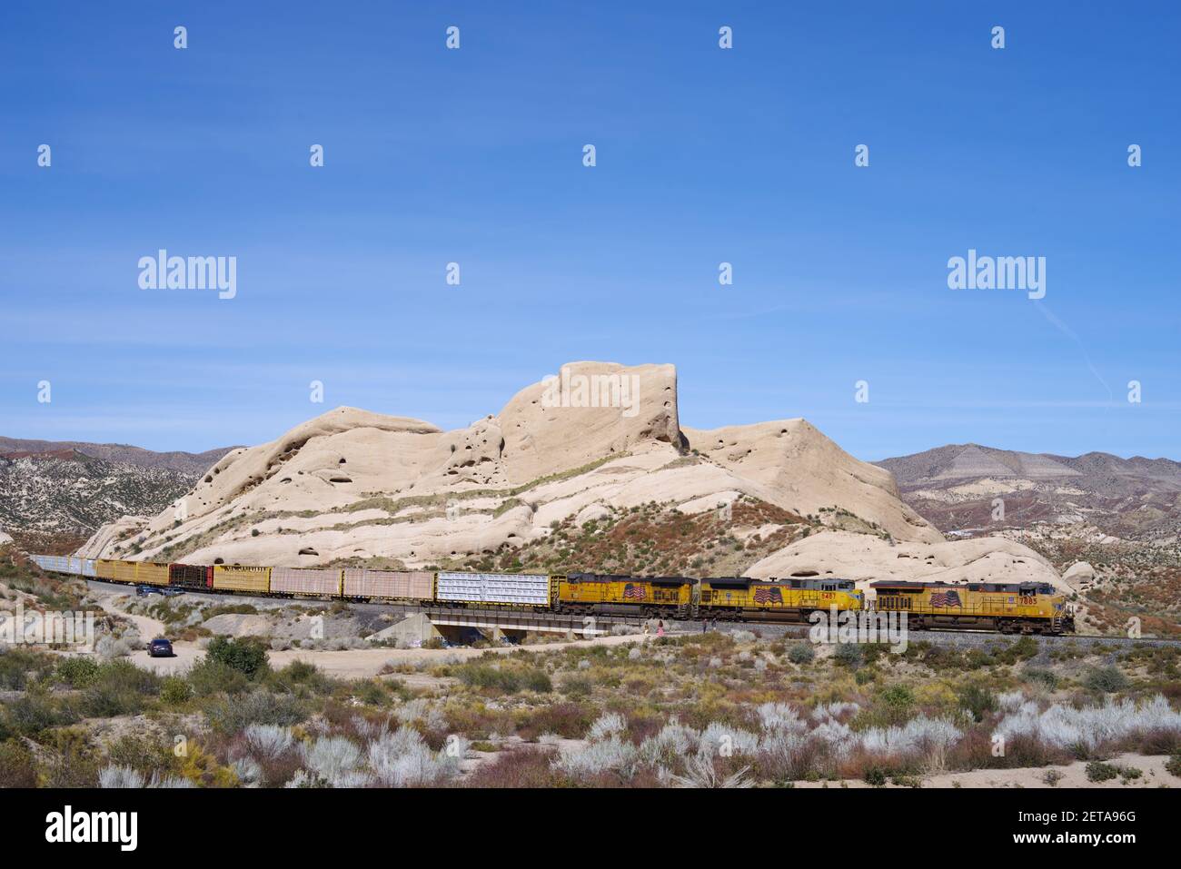 Union Pacific Railroad train traveling through the Mojave Desert shown against the Mormon Rocks ...