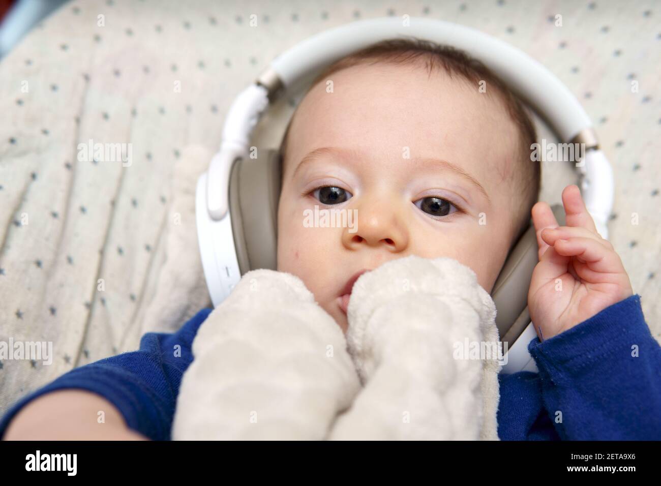 three-month-old baby listening to music with music headphones lying ...