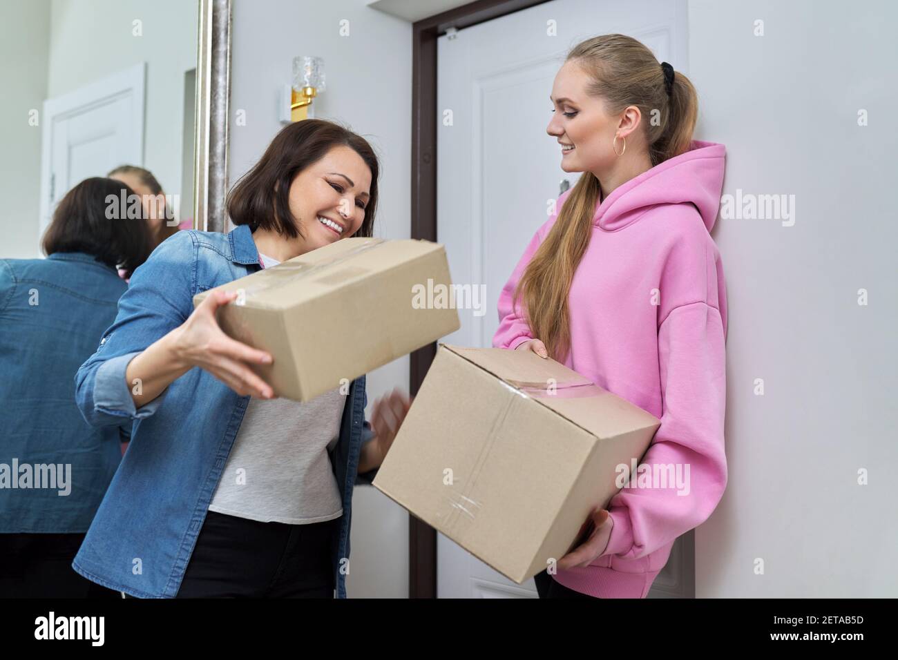 Delivery of goods, two women with cardboard boxes near front door of ...