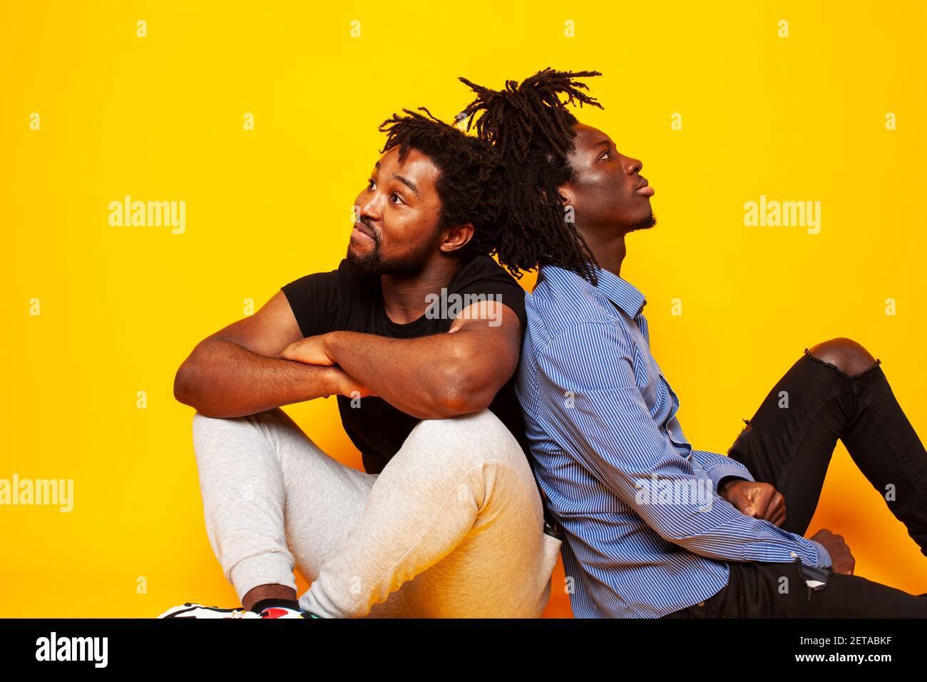 two african american guys posing cheerful together on yellow background ...