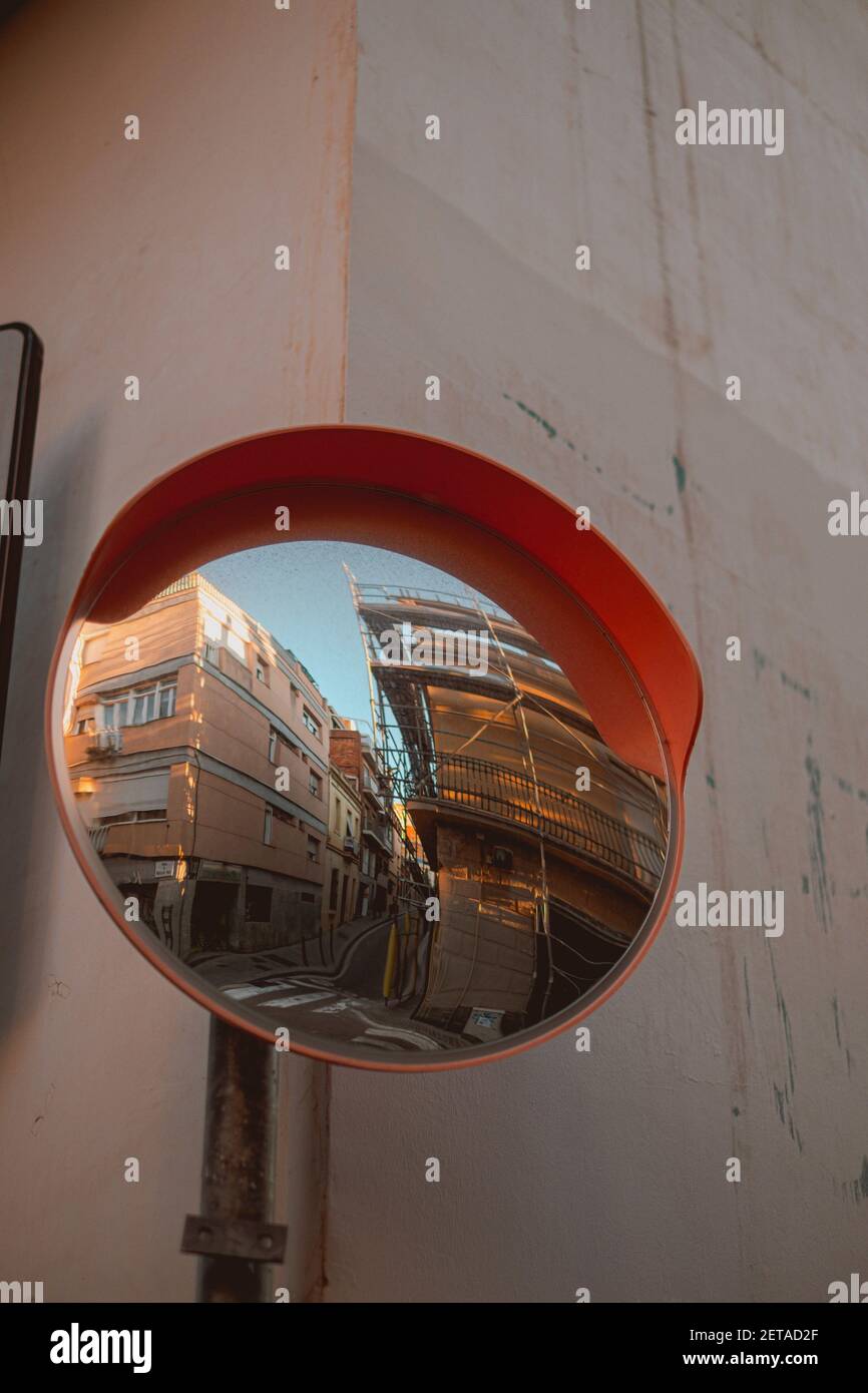 A circular road safety mirror with the reflection of street buildings ...