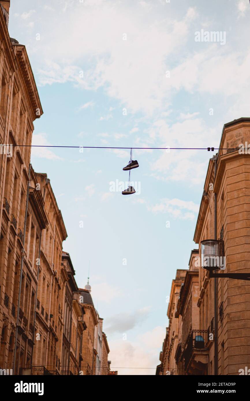 A view of sneakers hanging on the rope between old street buildings ...