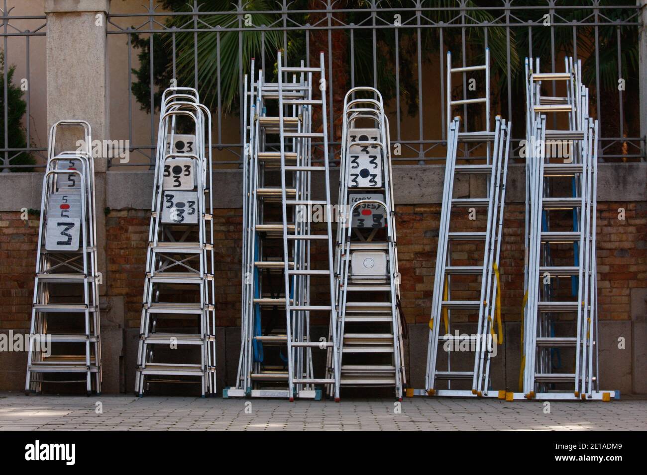Many ladders leaned on the fence of a building Stock Photo - Alamy