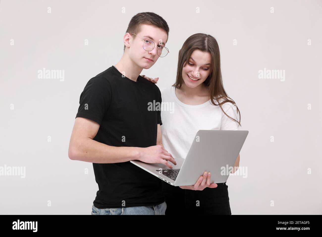 Portrait of a smiling teens boy and girl holding laptop computer while ...