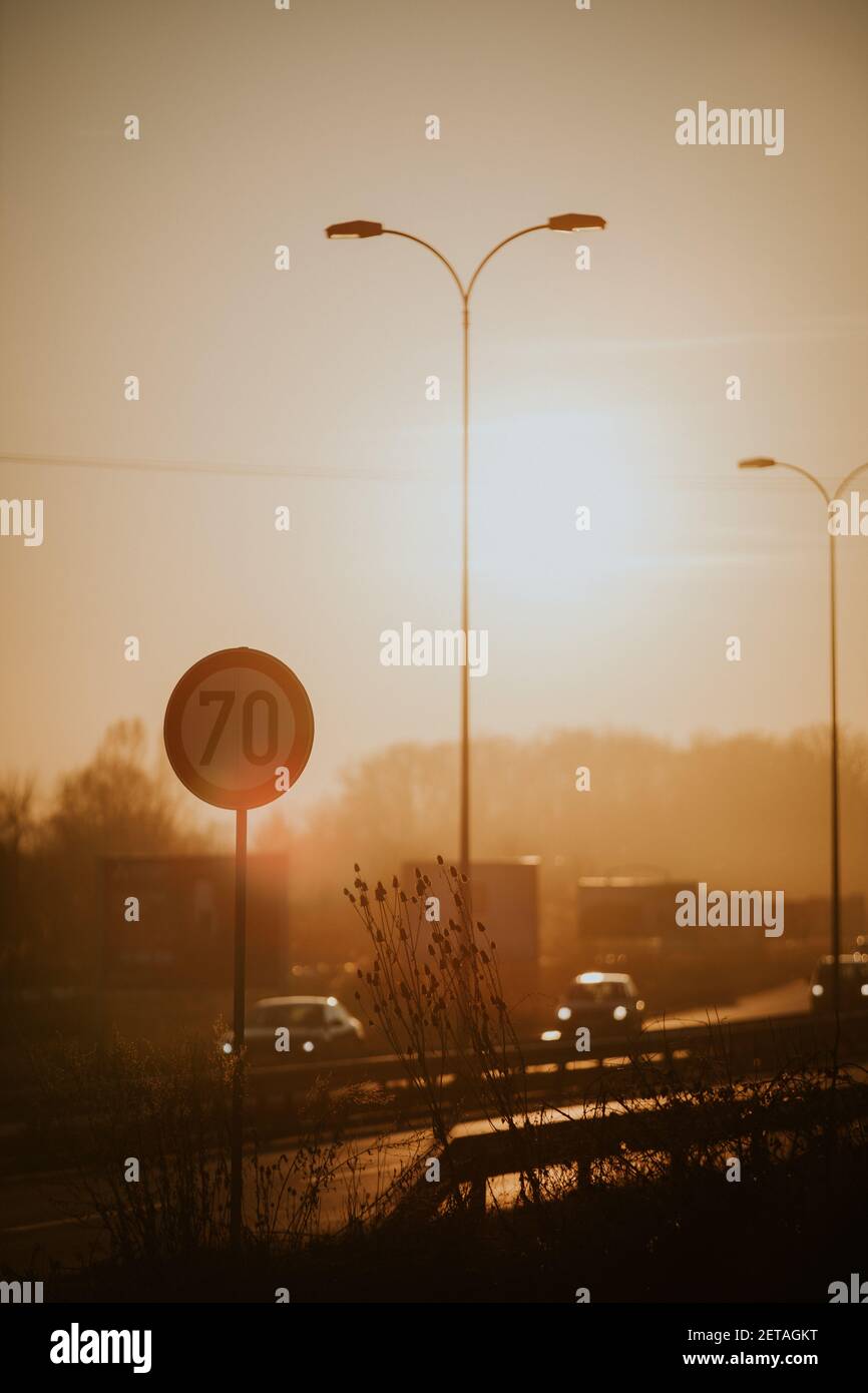 A vertical shot of a round speed limit road sign on the road at suns ...