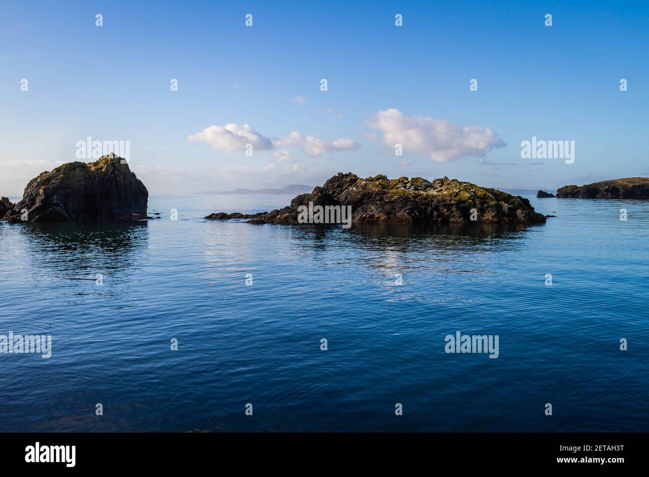 Rocks protruding from the surrounding blue ocean waters Stock Photo - Alamy