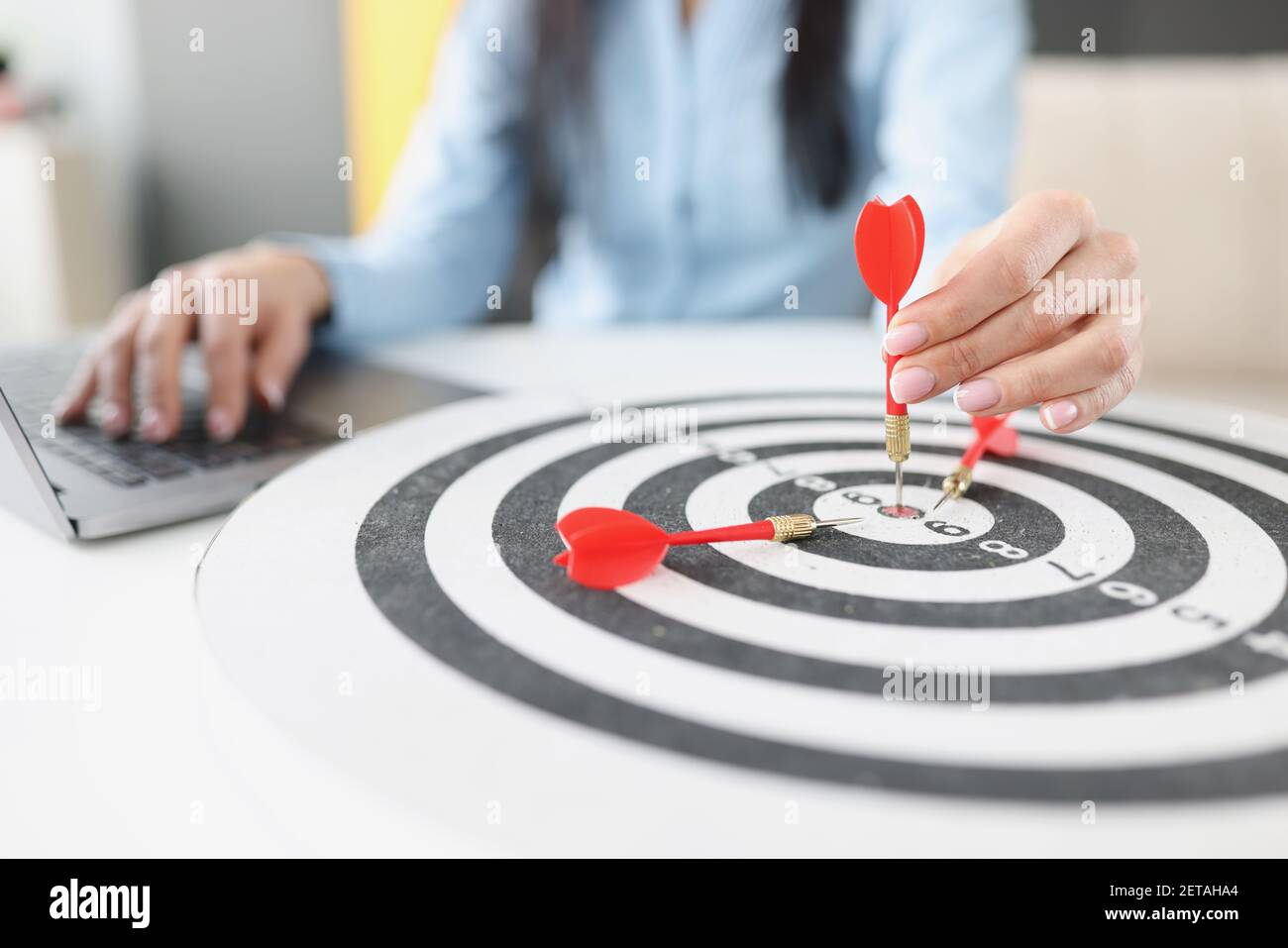 Female hand holding dart in dart center at work table Stock Photo - Alamy