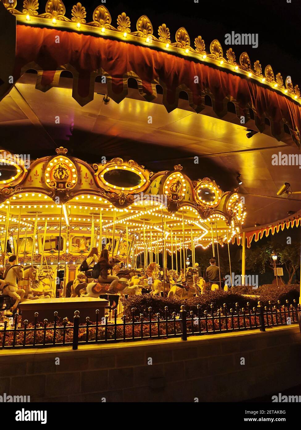 a vertical shot of rotating horses carousel with yellow lights in the ...