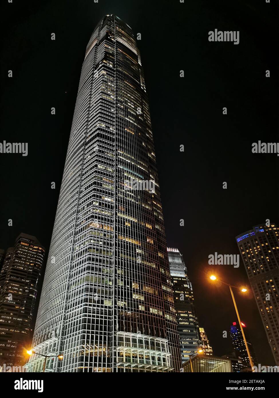 a vertical low angle shot of a high rise building with street and house ...