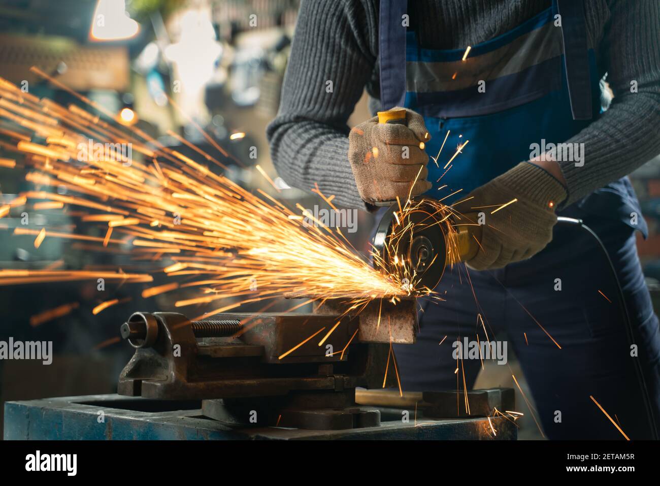 Locksmith in special clothes and goggles works in production. Metal ...
