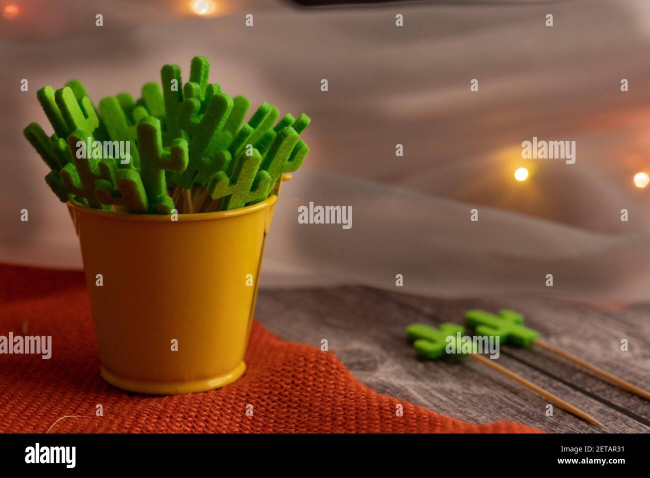 A closeup shot of a yellow bucket filled with cactus-shaped toothpicks ...