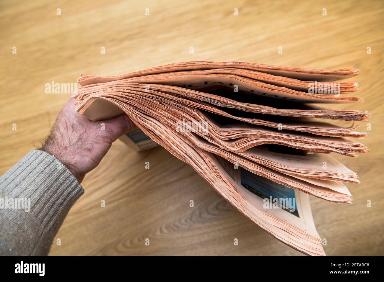Male hand holding stack of generic business newspaper defocused blur ...