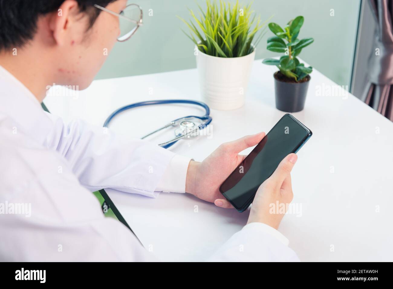 Asian doctor young handsome man smiling using working or holding with ...