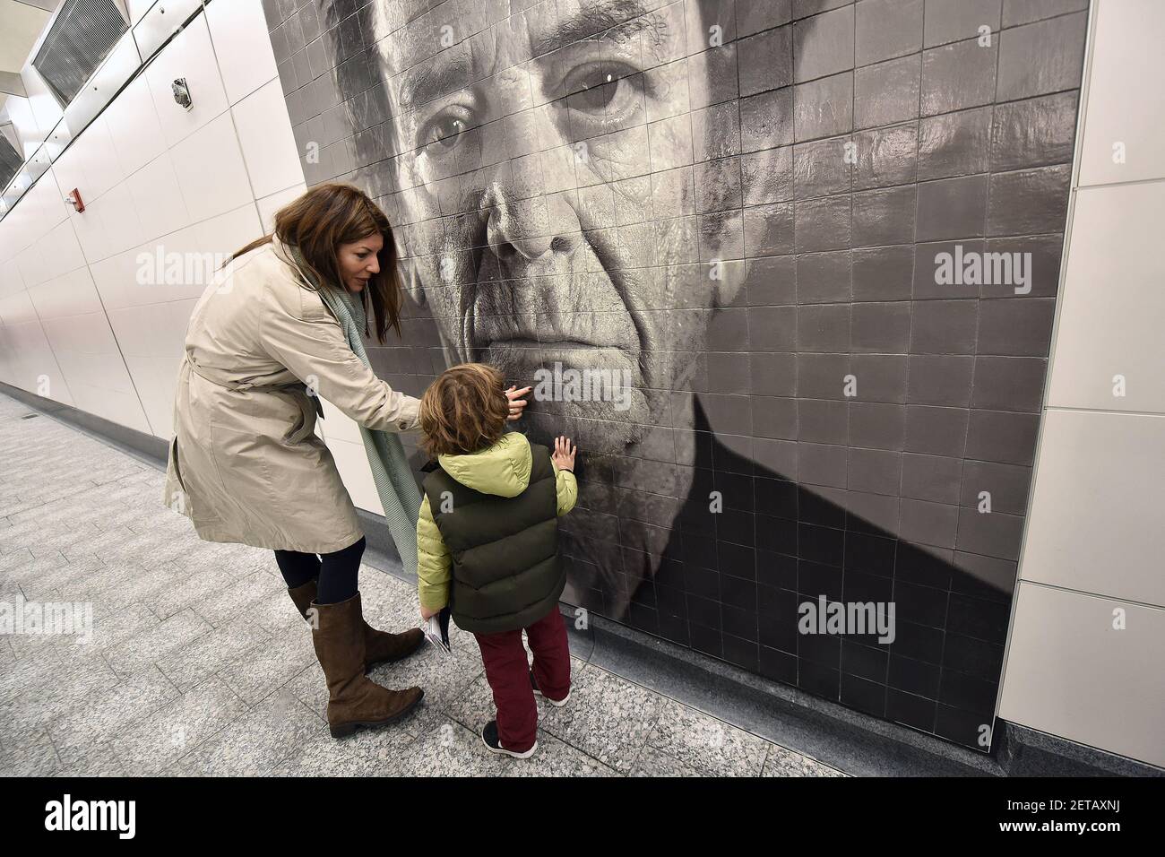 Commuters touch a portrait of musician Lou Reed by artist Chuck Close ...