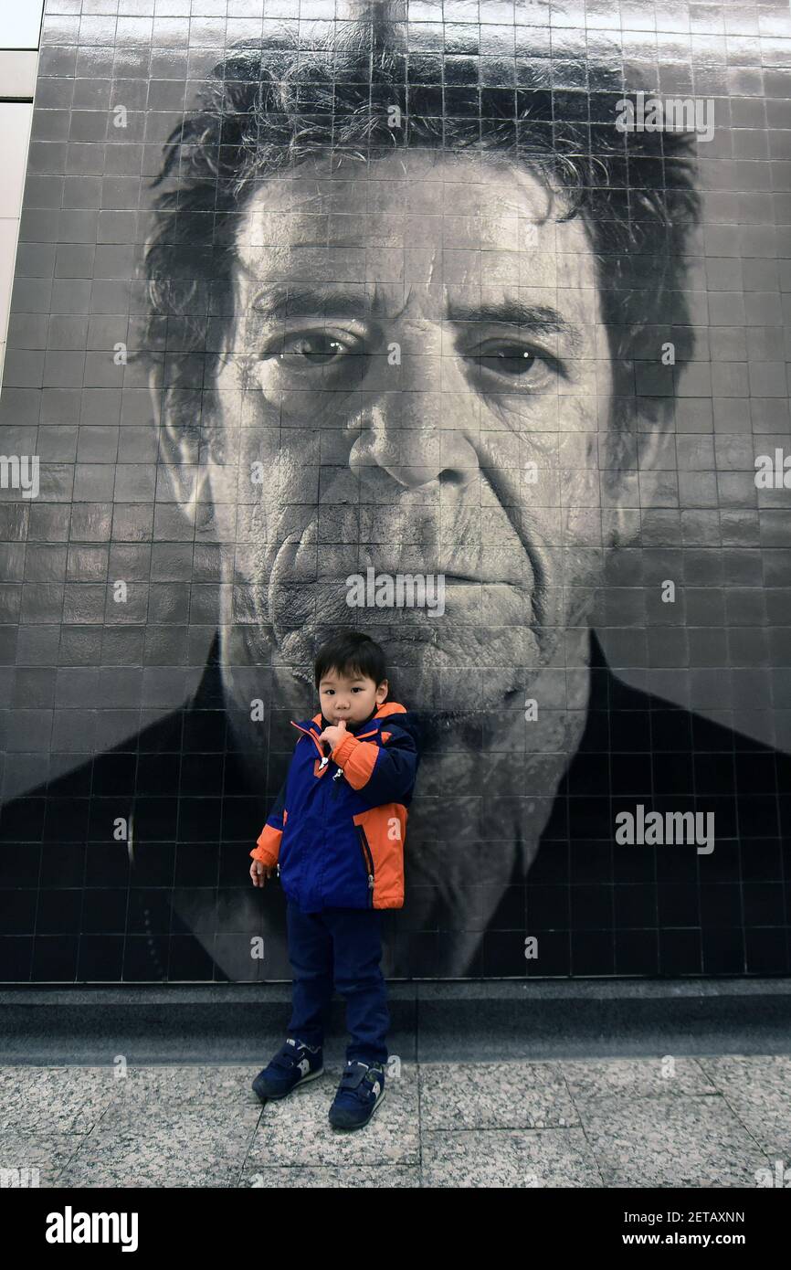 A child stands in front of a portrait of musician Lou Reed by artist ...