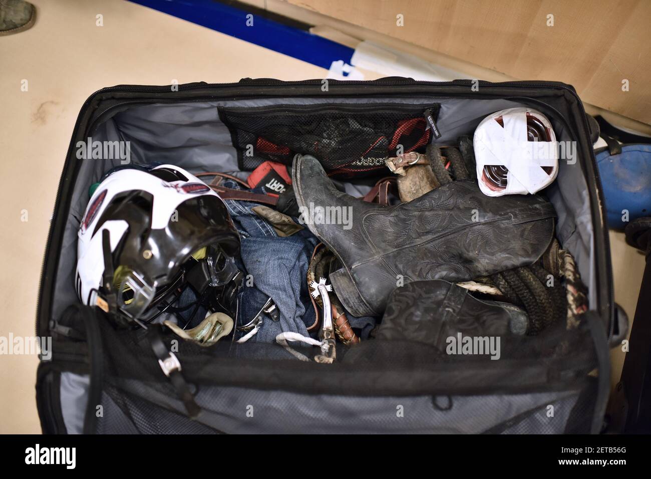 A protective bull riding helmet and and a cowboy boot sit inside the ...