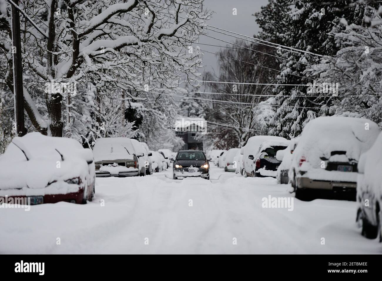 A car drives down a snowy street in North Portland, Ore., on January 11 ...