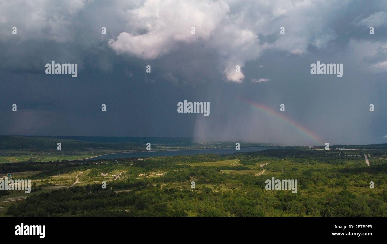 A mesmerizing aerial view of a rainbow during heavy rain above a land ...