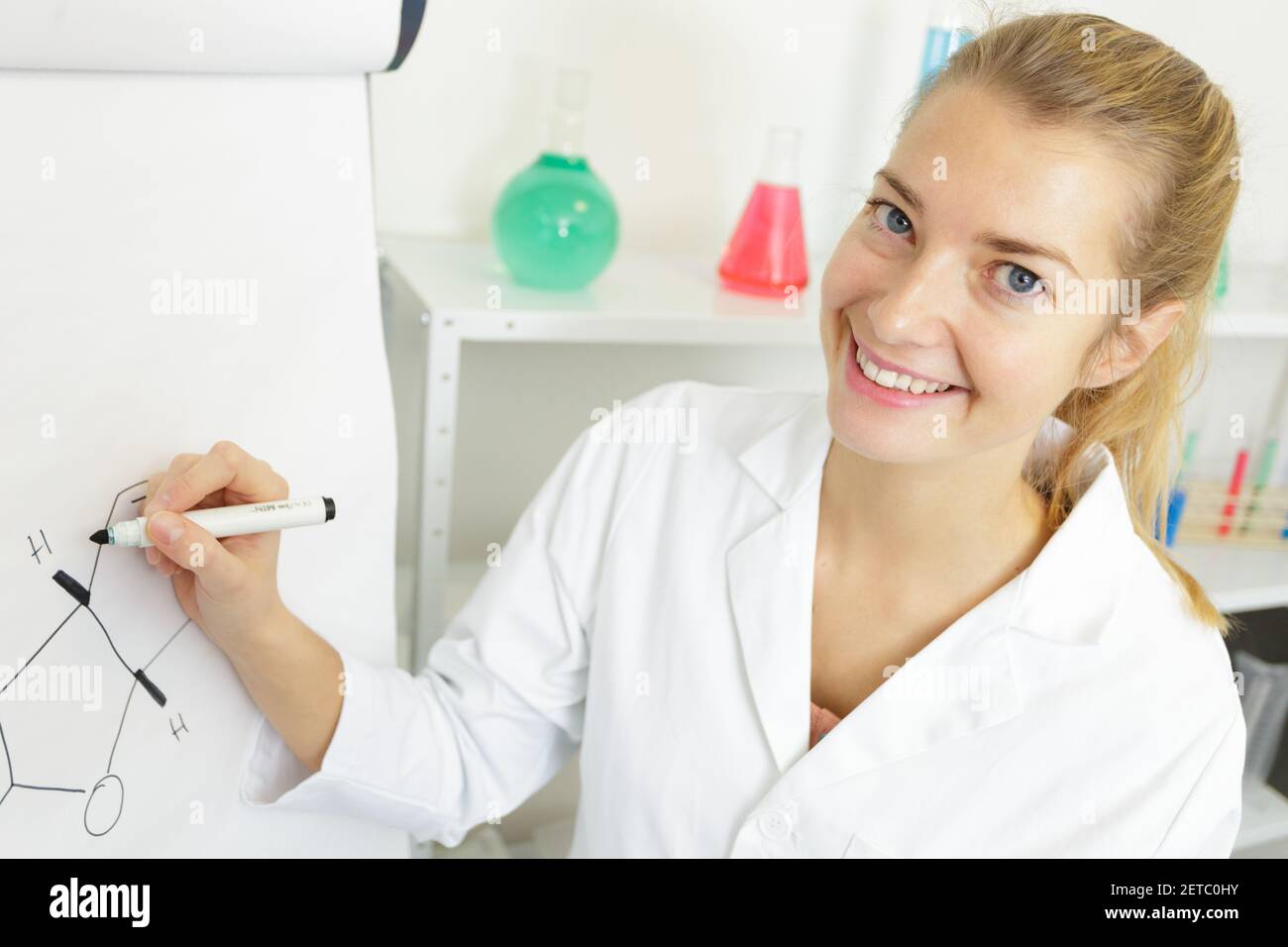 beautiful young woman scientist professor writing chemistry formulas on ...