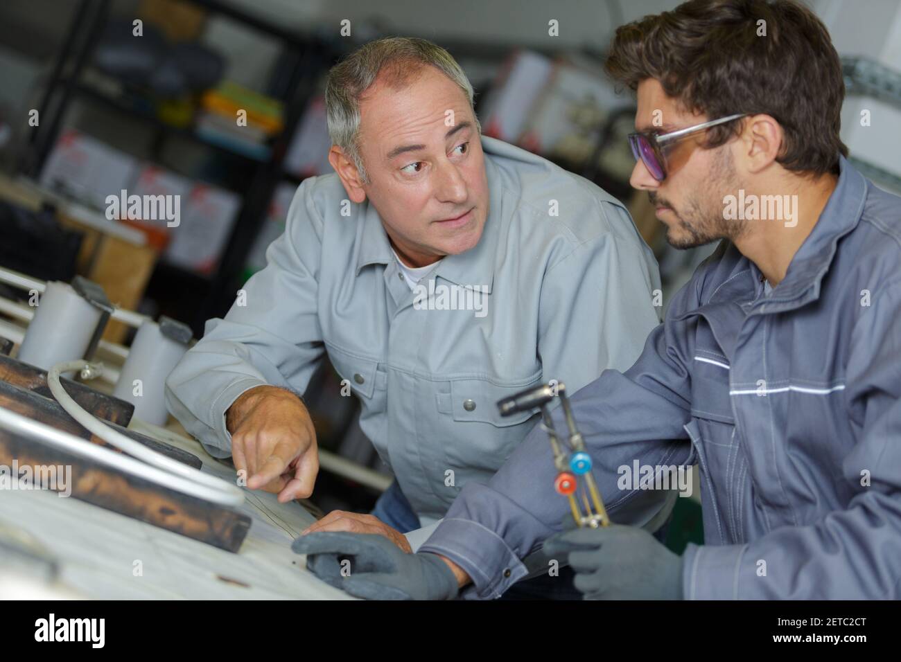 man instructing colleague how to use gas torch Stock Photo - Alamy
