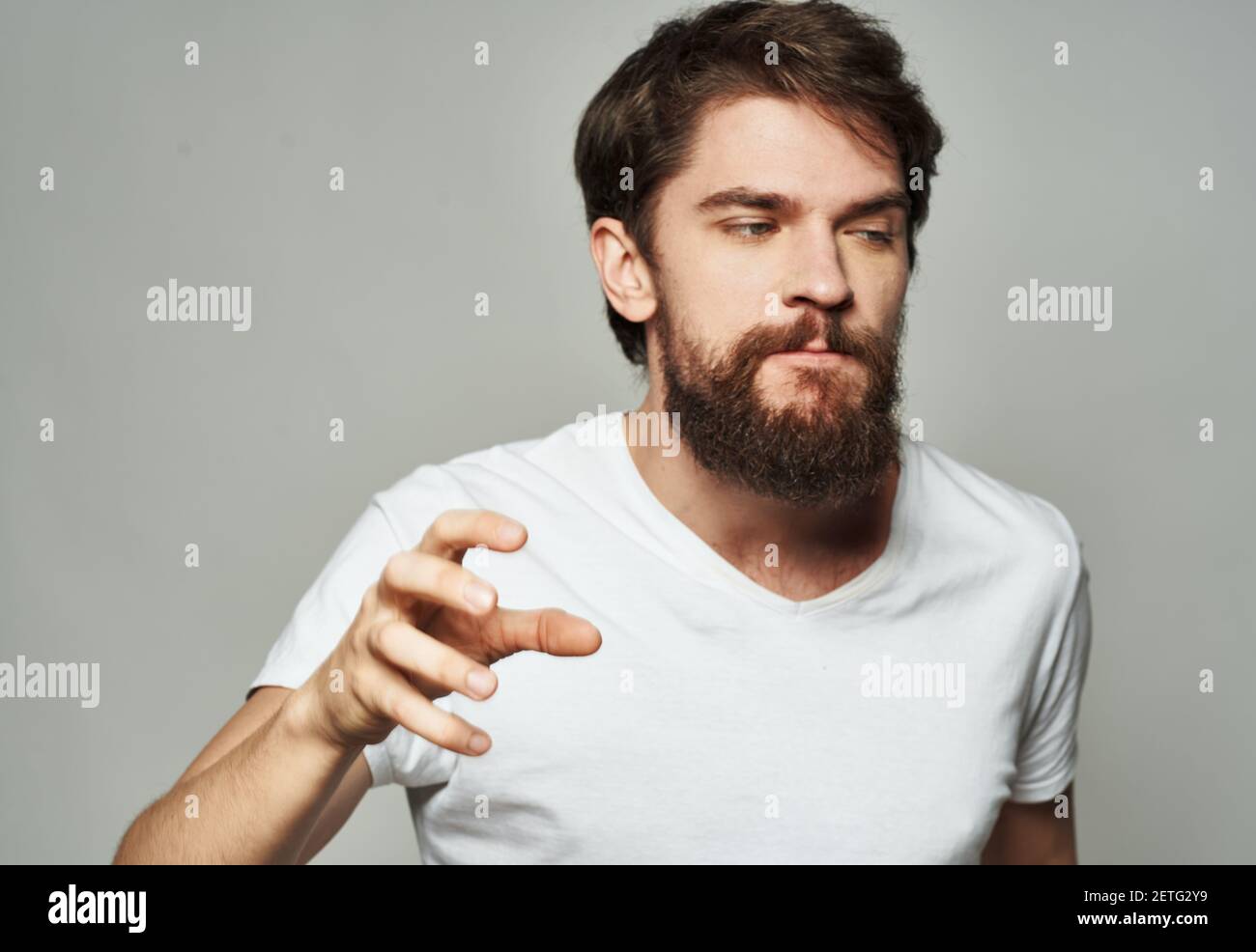 emotional man gesturing with his hands on a light background aggression ...