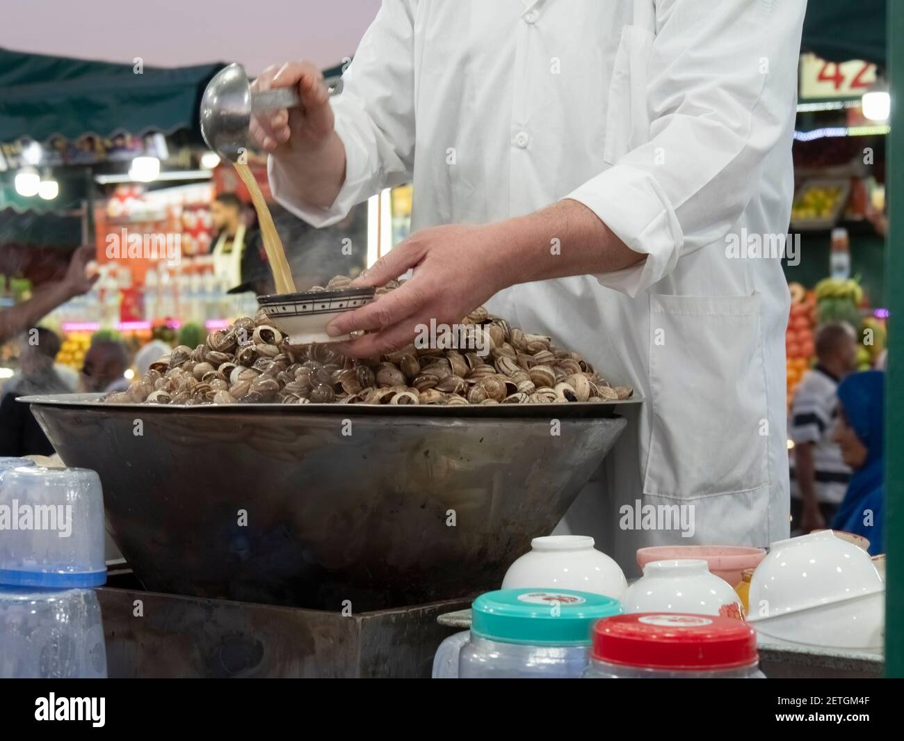 cook serving escargot at an outdoor restaurant in the jemaa el-fnaa ...
