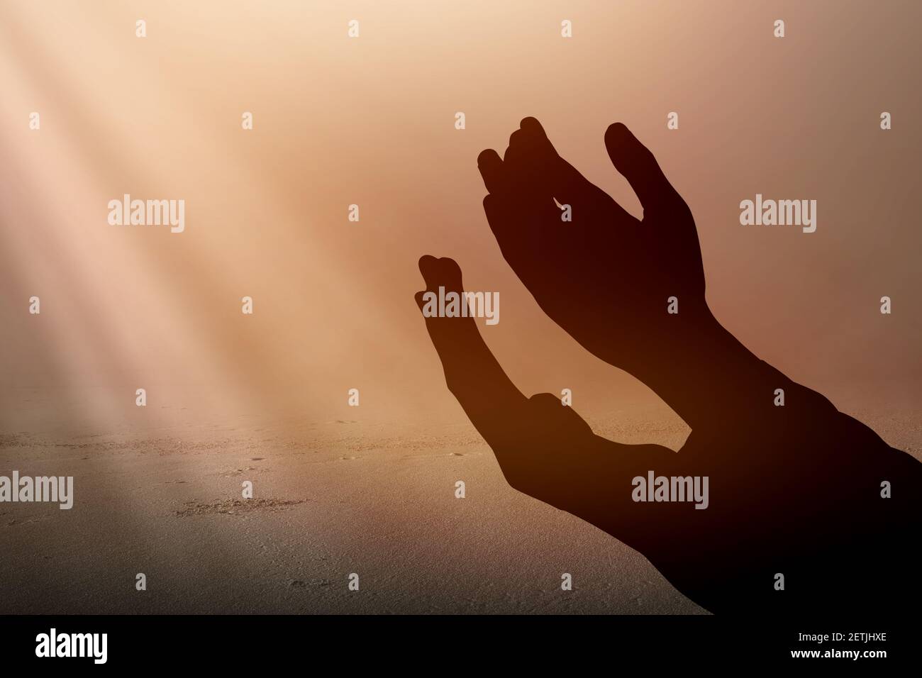 Silhouette of Muslim man standing while raised hands and praying with ...
