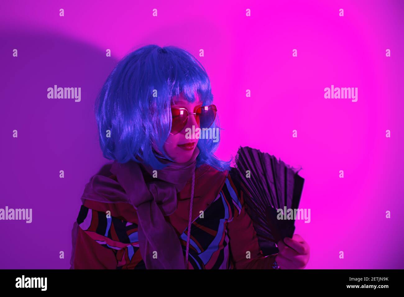 Little girl posing with a fan for a photo shoot on a fuchsia background ...