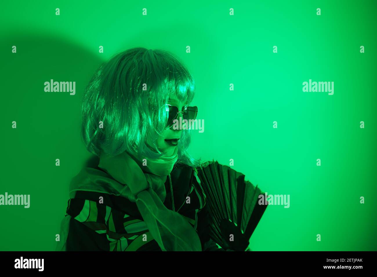 Little girl posing with a fan for a photo shoot on a green background ...