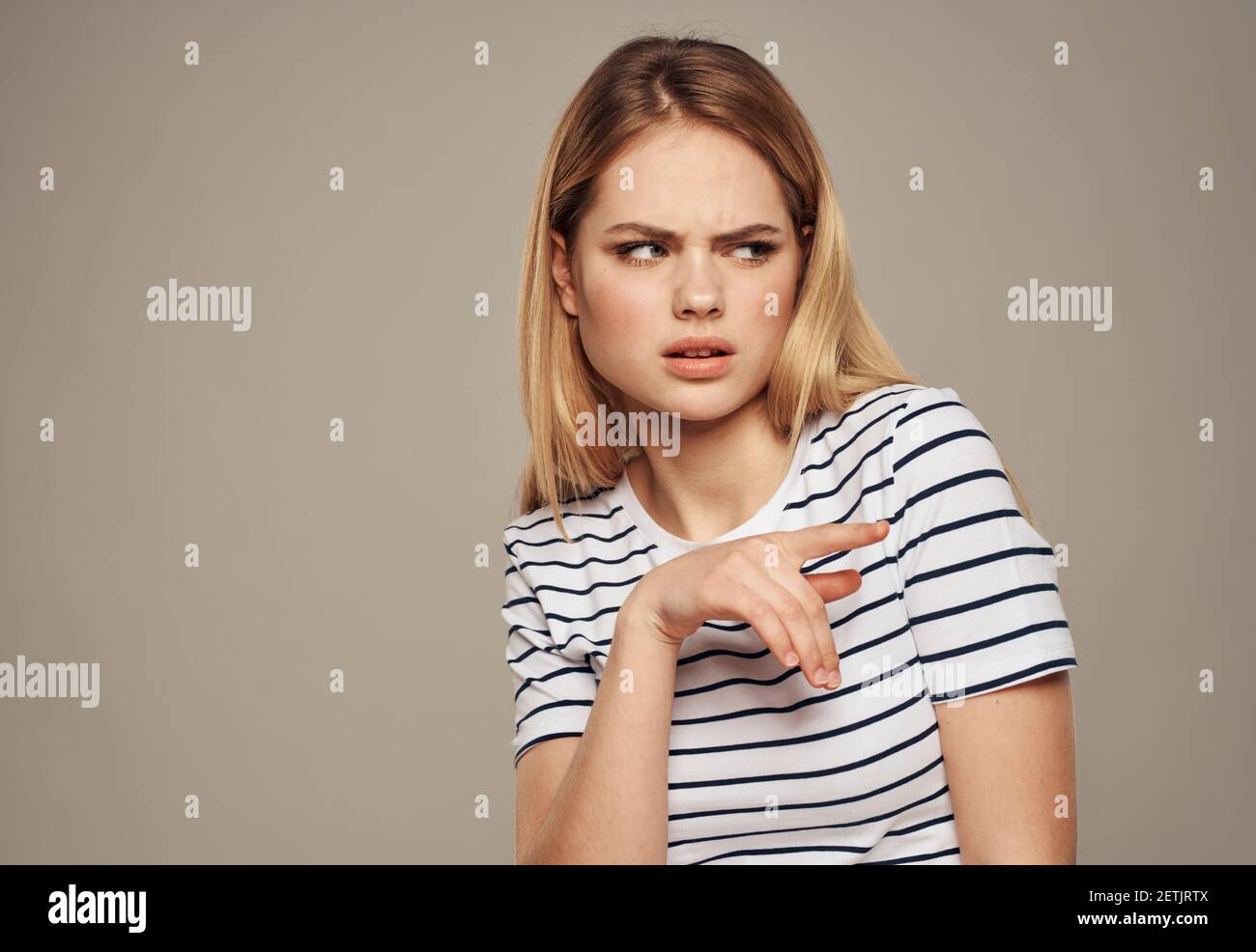 Blond woman with disgust looks to the side and beige background cropped ...
