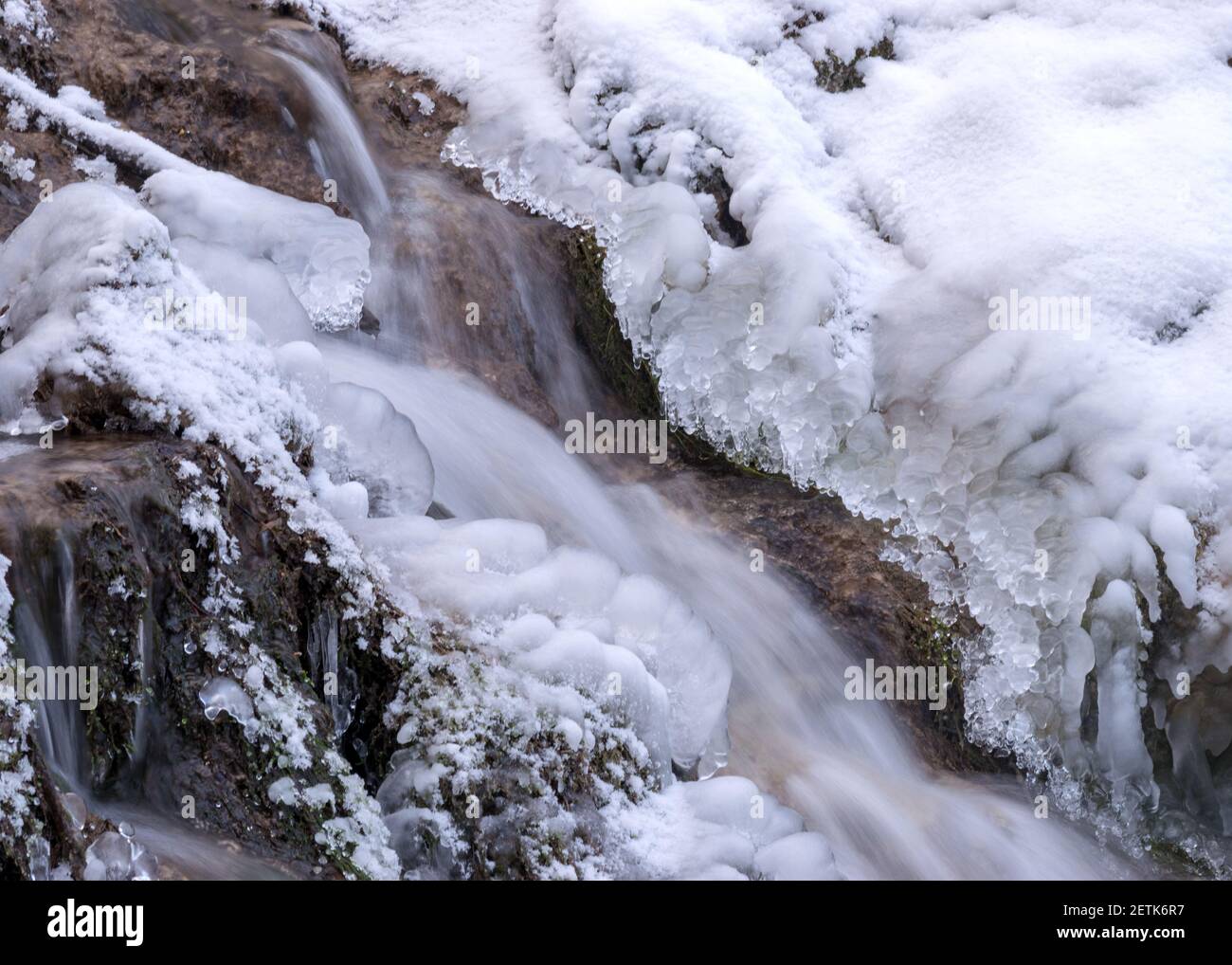 frozen fast flowing spring water, icy rocks and water stream, frosty ...