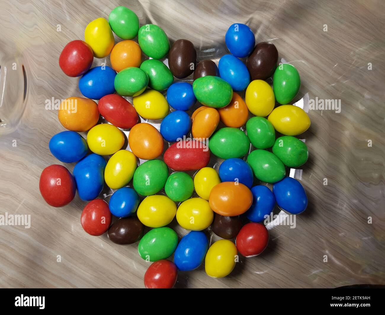Multicolored chocolate-covered nuts in a transparent plate Stock Photo ...