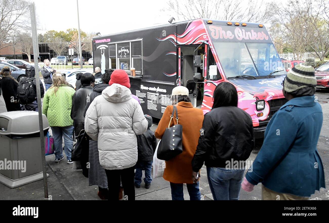 Women line up at The Improper Pig's food truck, The Oinker, to receive ...