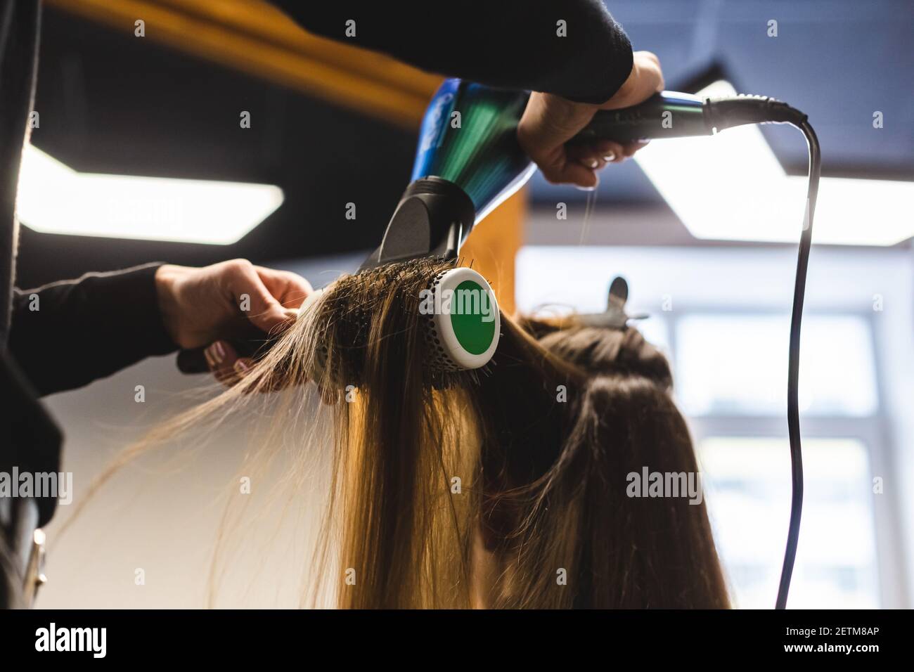 Master woman hairdresser dries the girl's hair with a hairdryer and ...