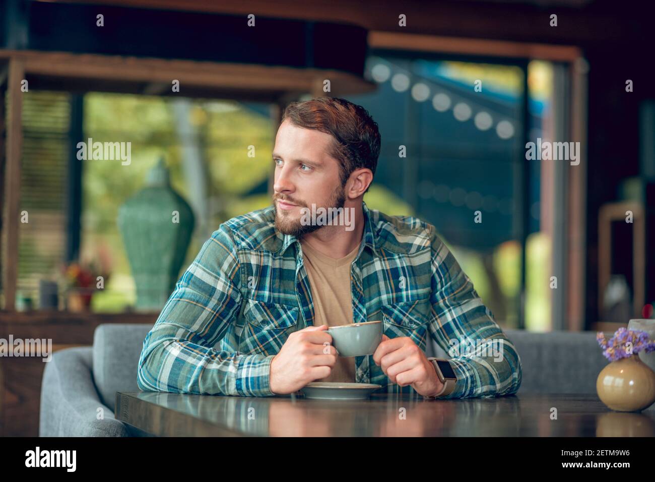 Attractive young man at table in cafe Stock Photo - Alamy